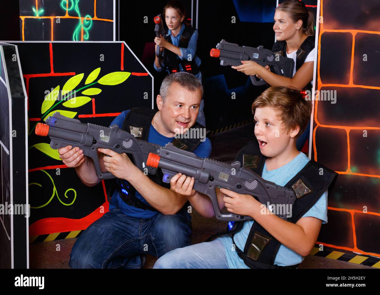 Happy teen boy with laser gun having fun on lasertag arena with his ...