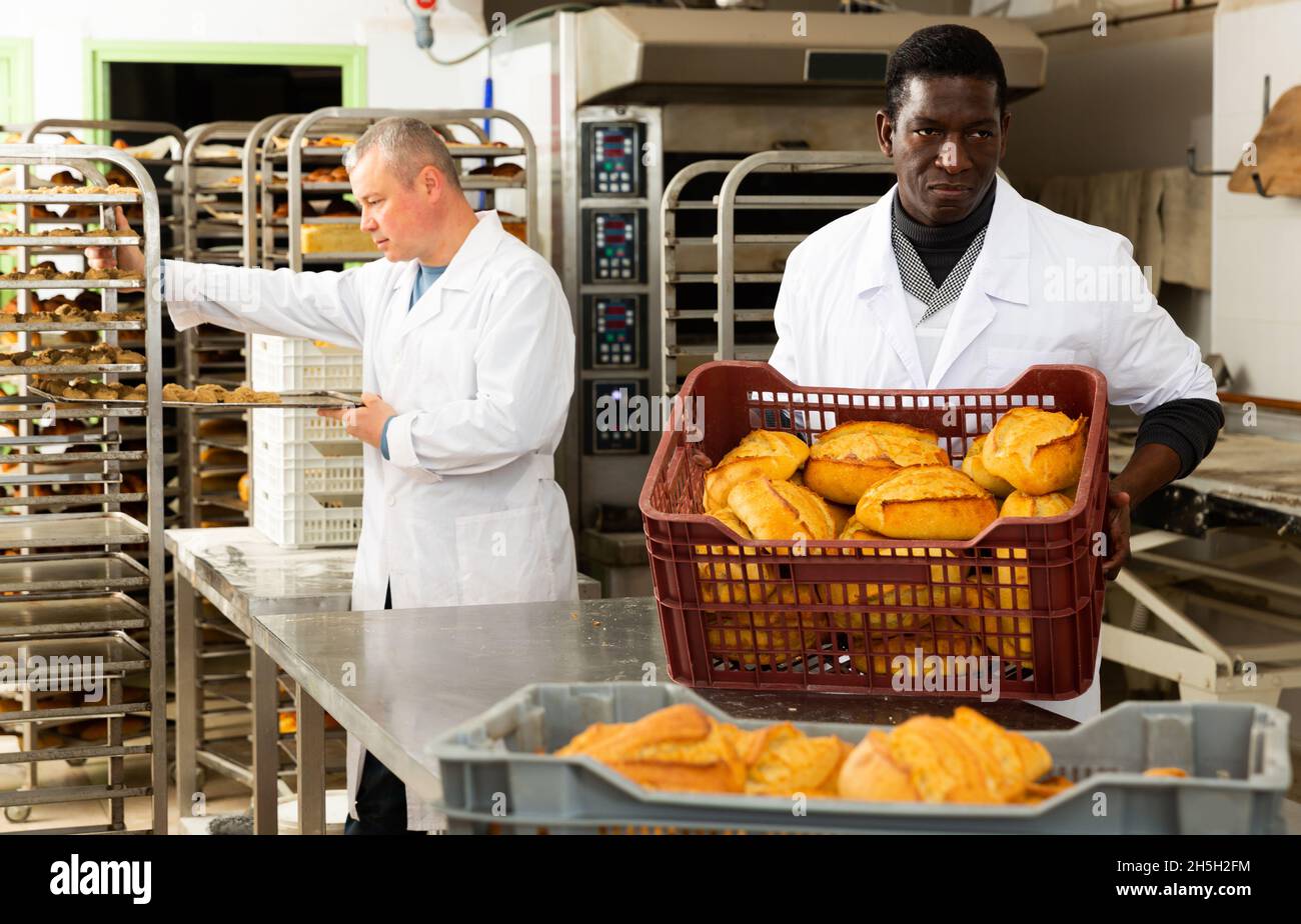 Two bakers arranging baked bread in bakery Stock Photo - Alamy