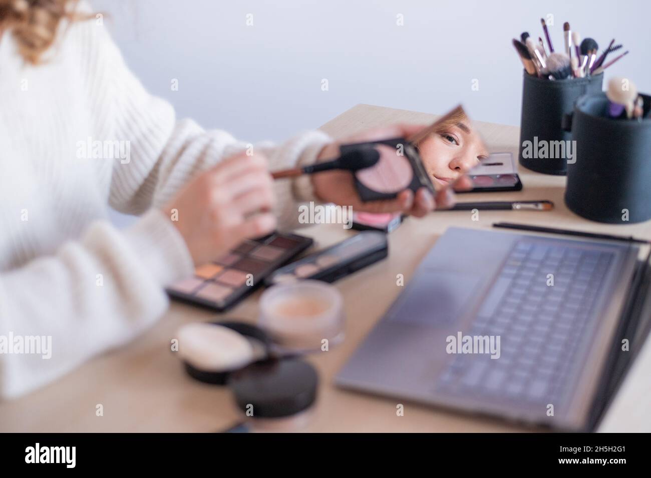 Online makeup tutorials. A woman watches a video training herself as a ...