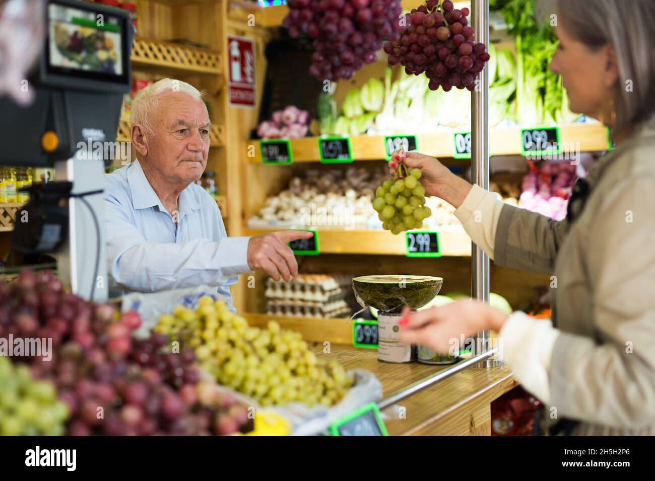 Senior salesman serving woman customer in greengrocer Stock Photo - Alamy