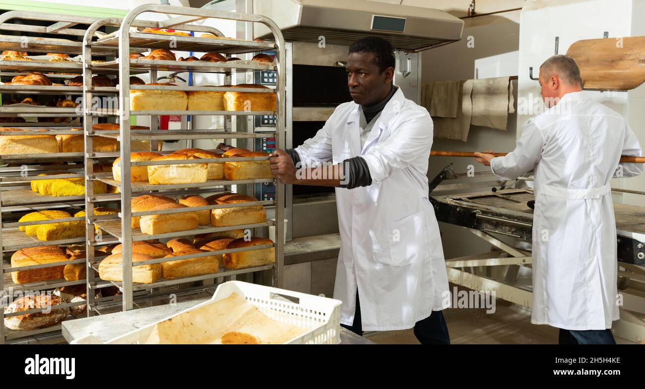 Baker pushing trolley with baked bread Stock Photo - Alamy
