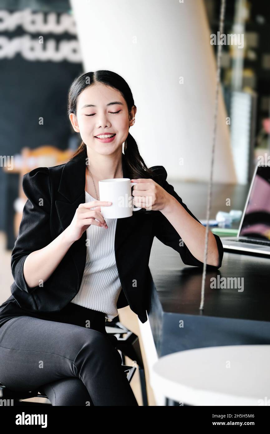 A female marketing manager is resting with a cup of coffee before ...