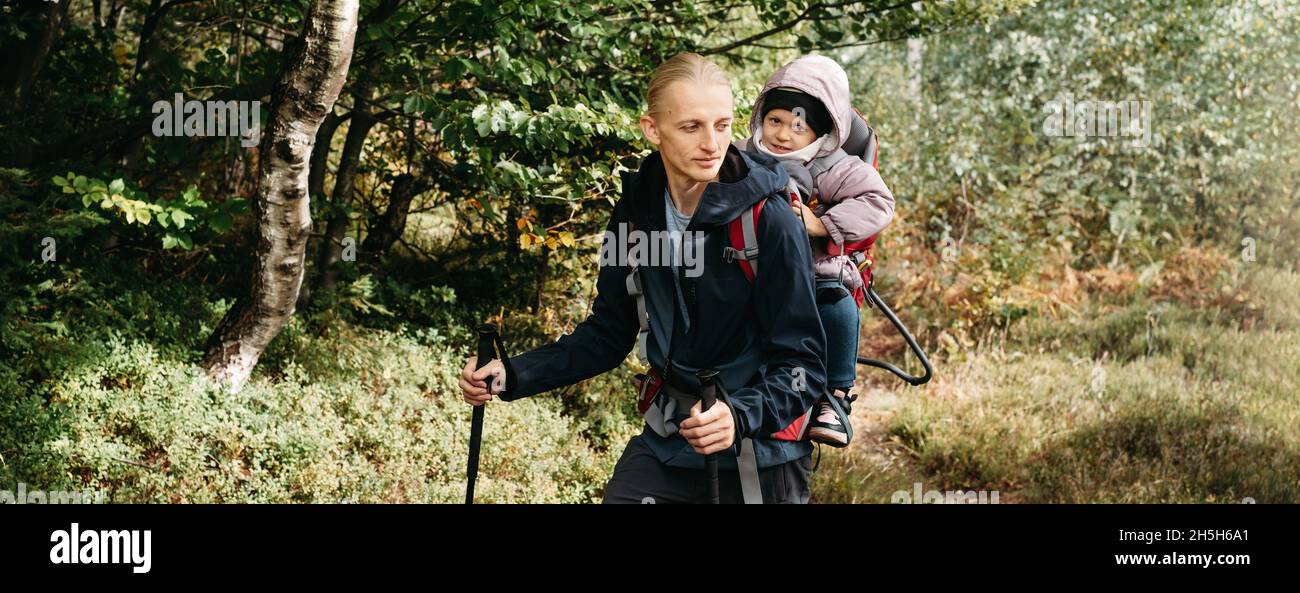 Banner Sleepy tired child walking with father in backpack in the ...
