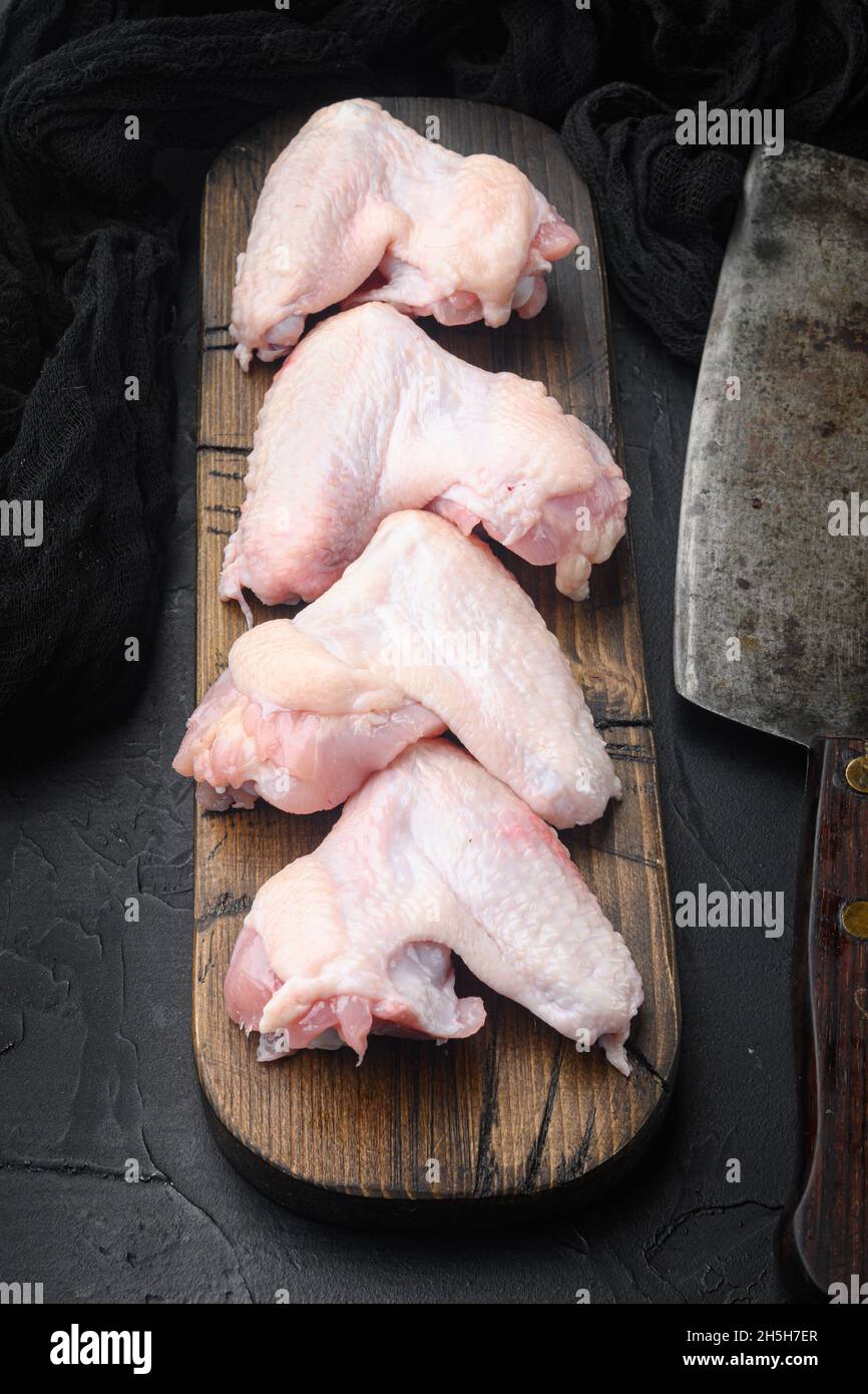 Chicken wings set , with old butcher cleaver knife, on black stone ...