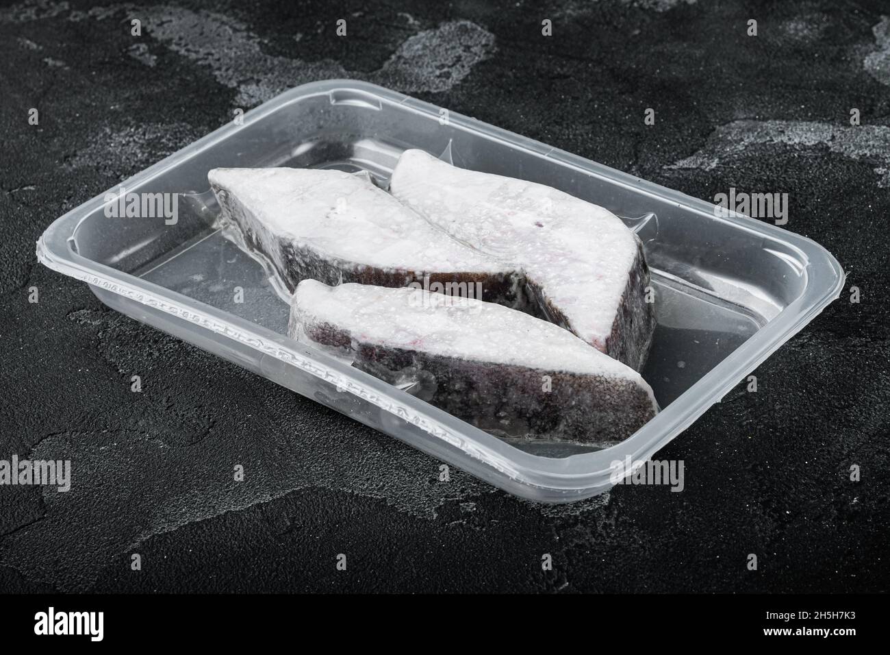 Frozen halibut pack set, on black dark stone table background, with ...