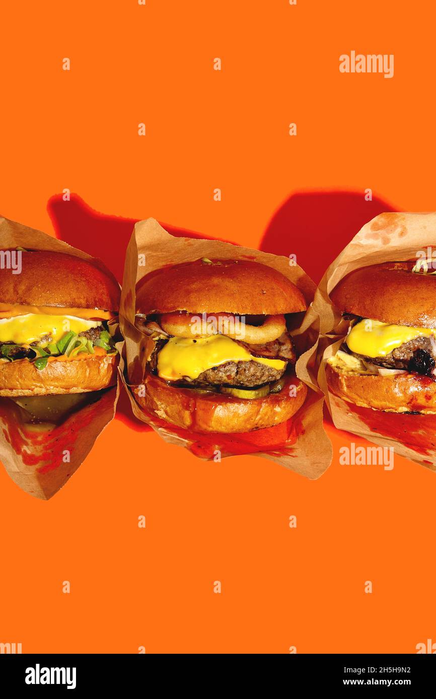 Three different burgers in a package on a bright orange background ...