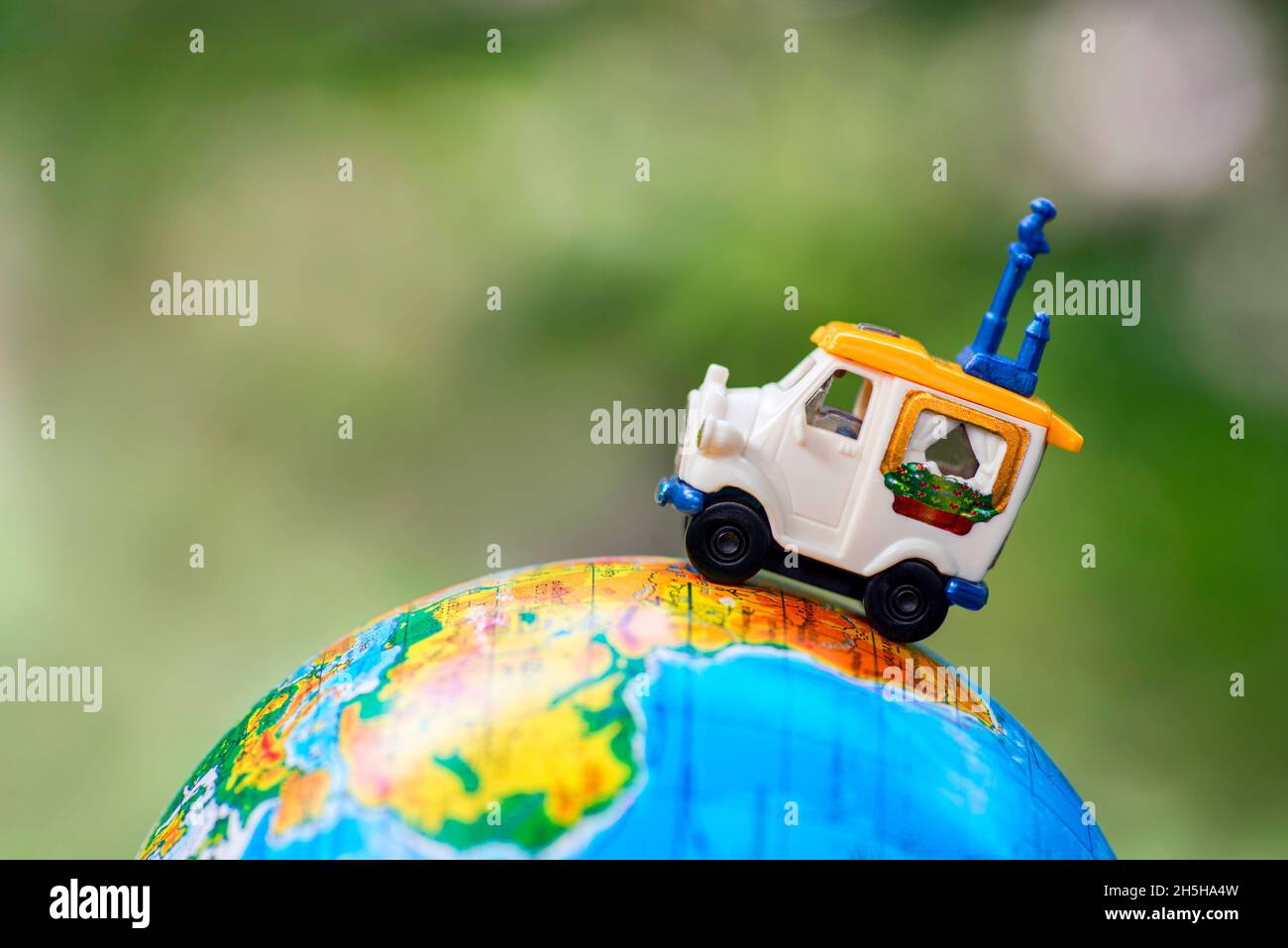 A car on globe on green background. Miniature car toy on globe. Travel ...