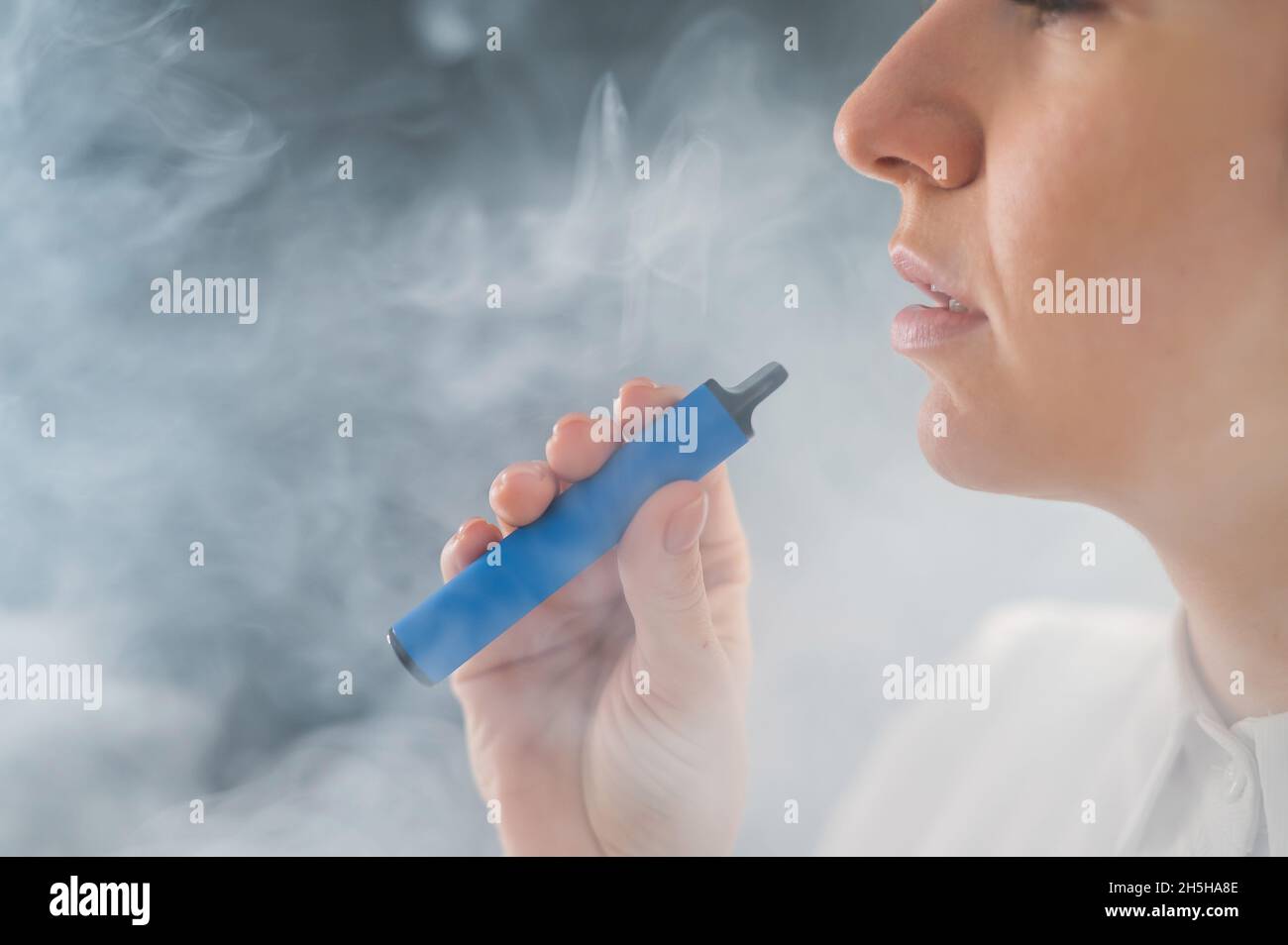 Caucasian woman smokes a disposable vape in the studio Stock Photo - Alamy