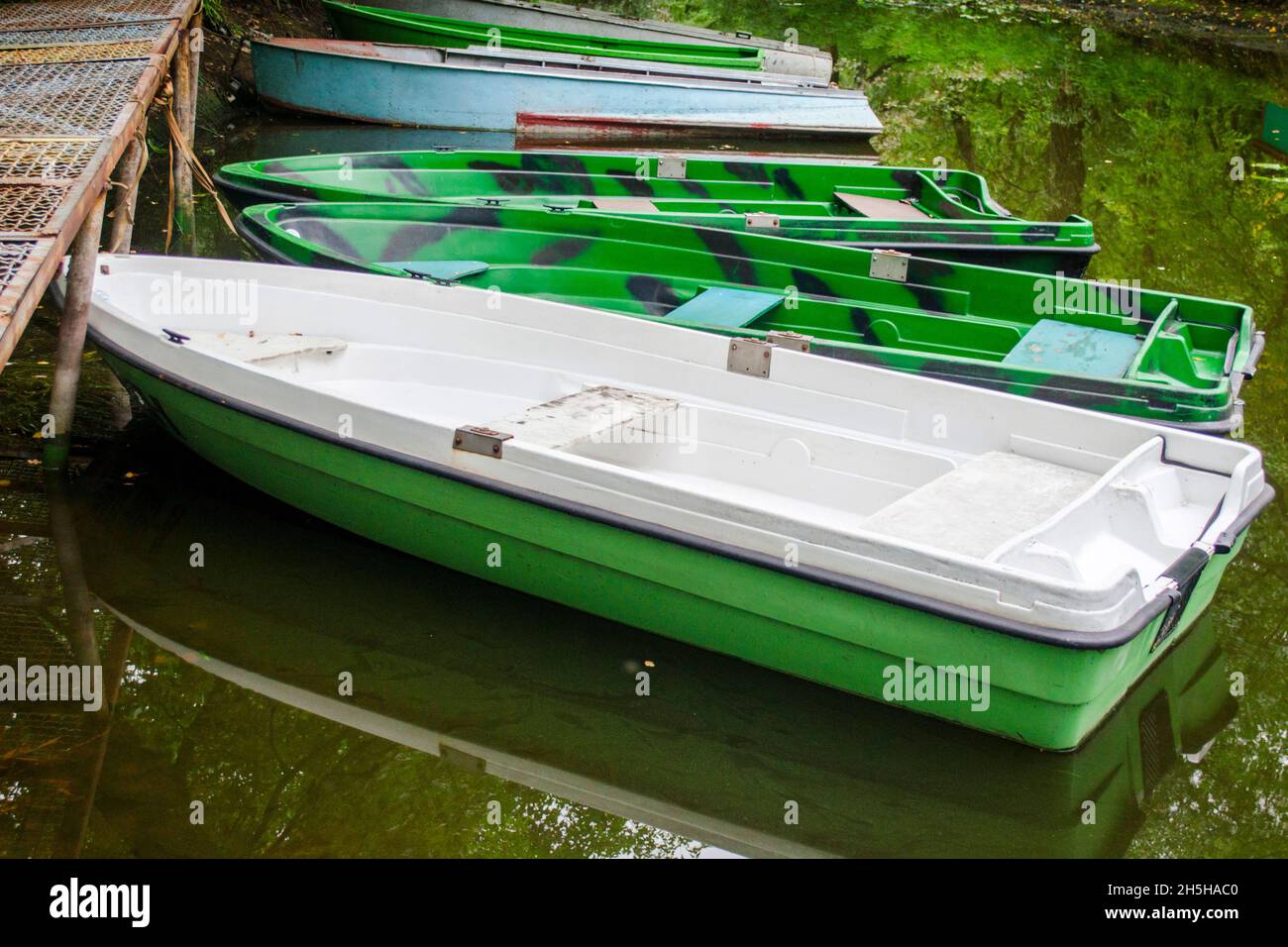 A line of rowing boats moored at an old jetty. Boats are moored at a ...