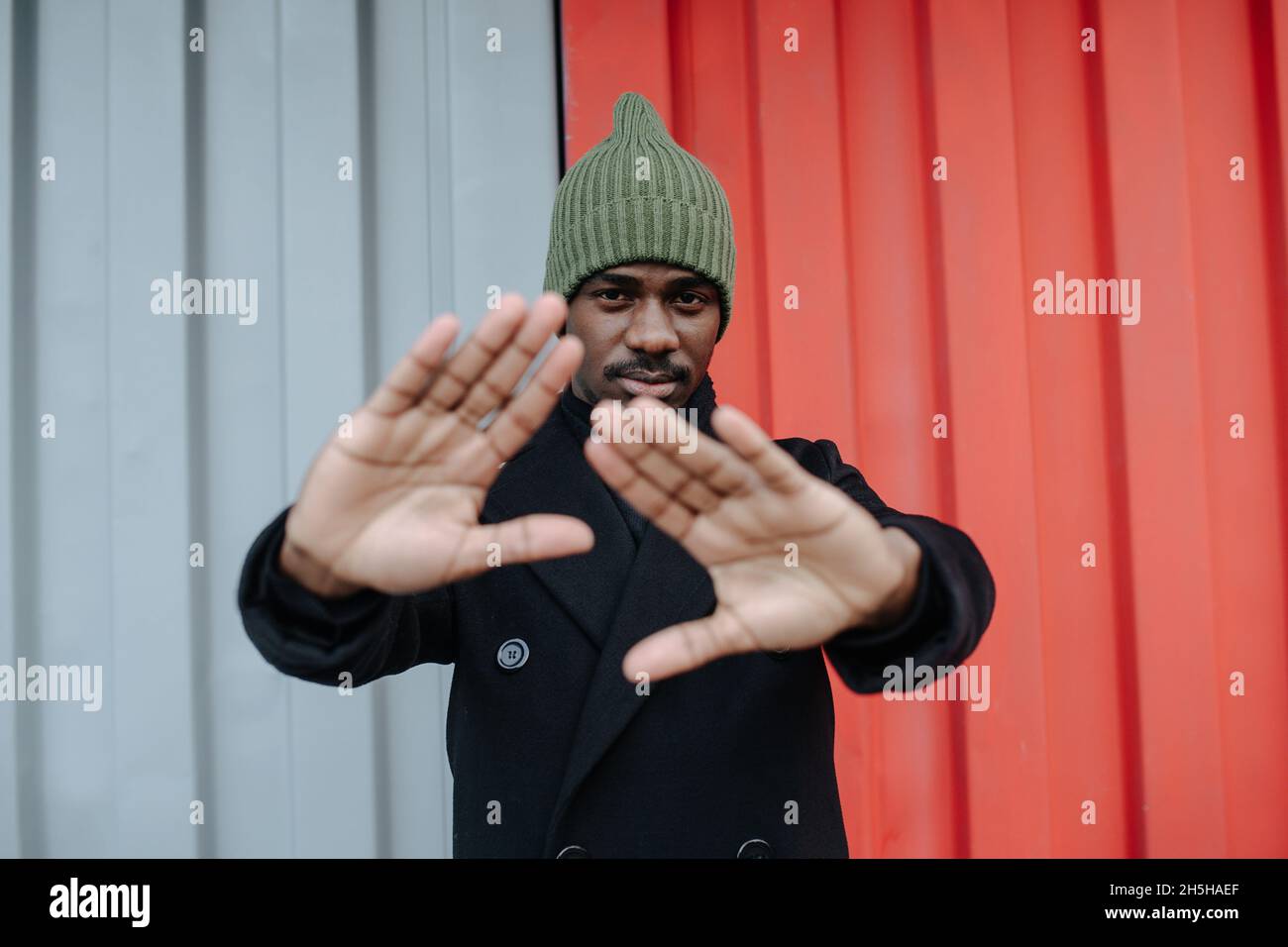 Insistend black man in a warm autumn coat blocking camera with his ...