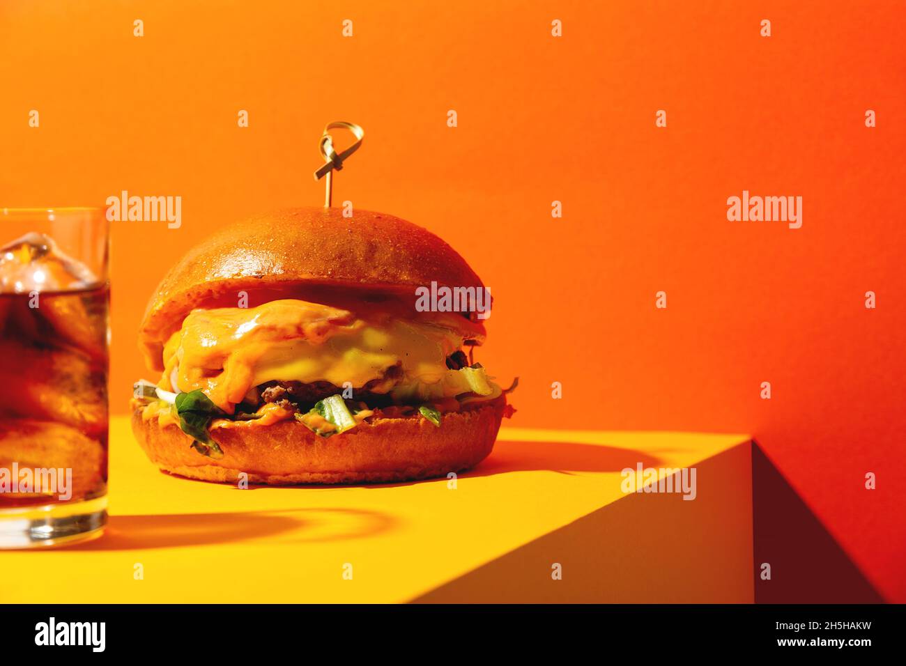 Big burger with cheese on bright orange and yellow background. American ...