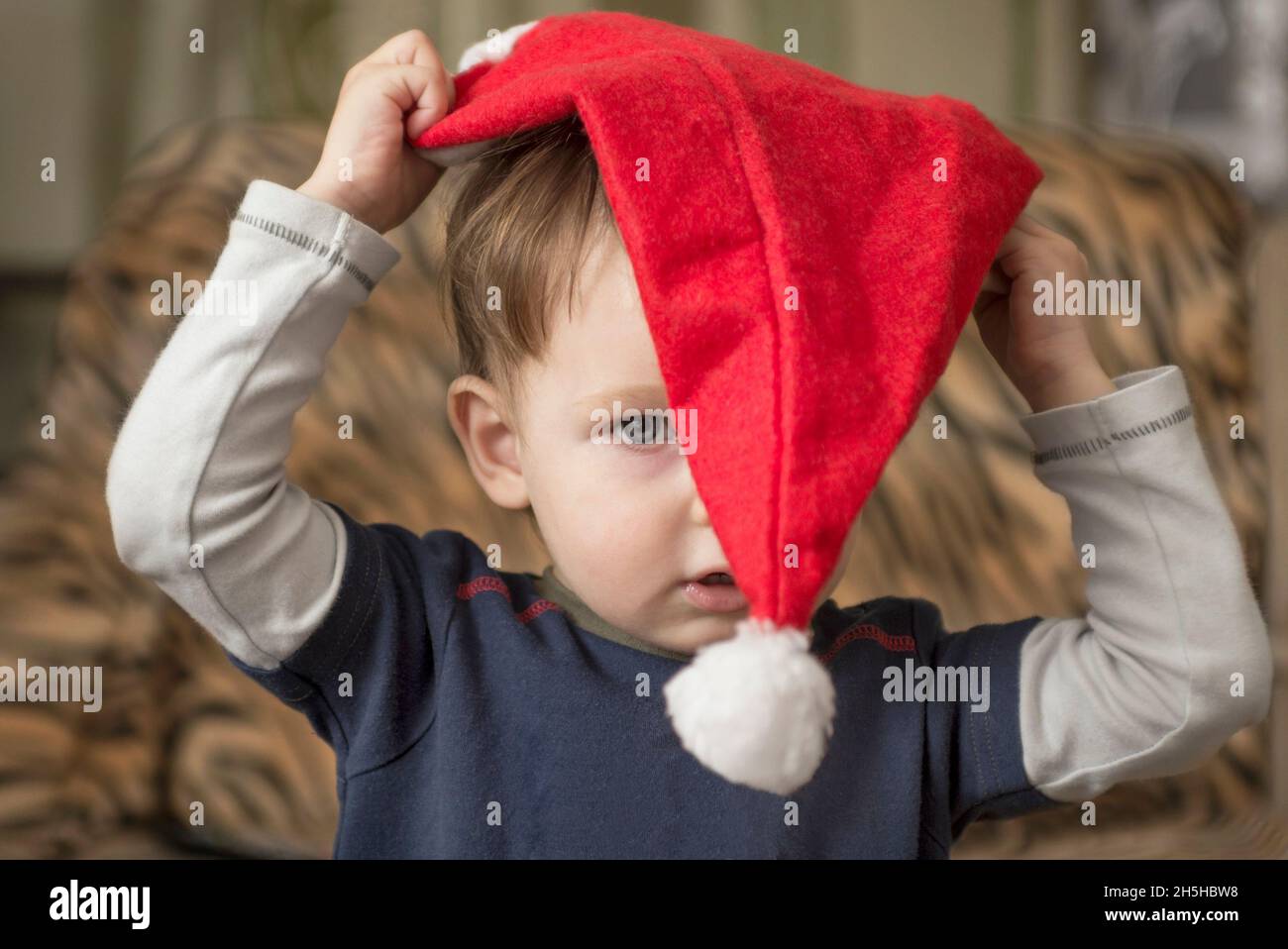 A small child is trying to put on a Santa Claus hat Stock Photo - Alamy
