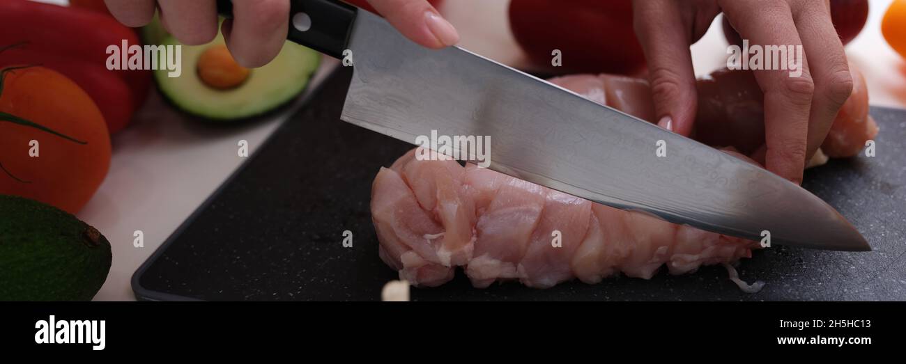 Woman hand cuts meat fillet with knife on board next to garlic Stock ...