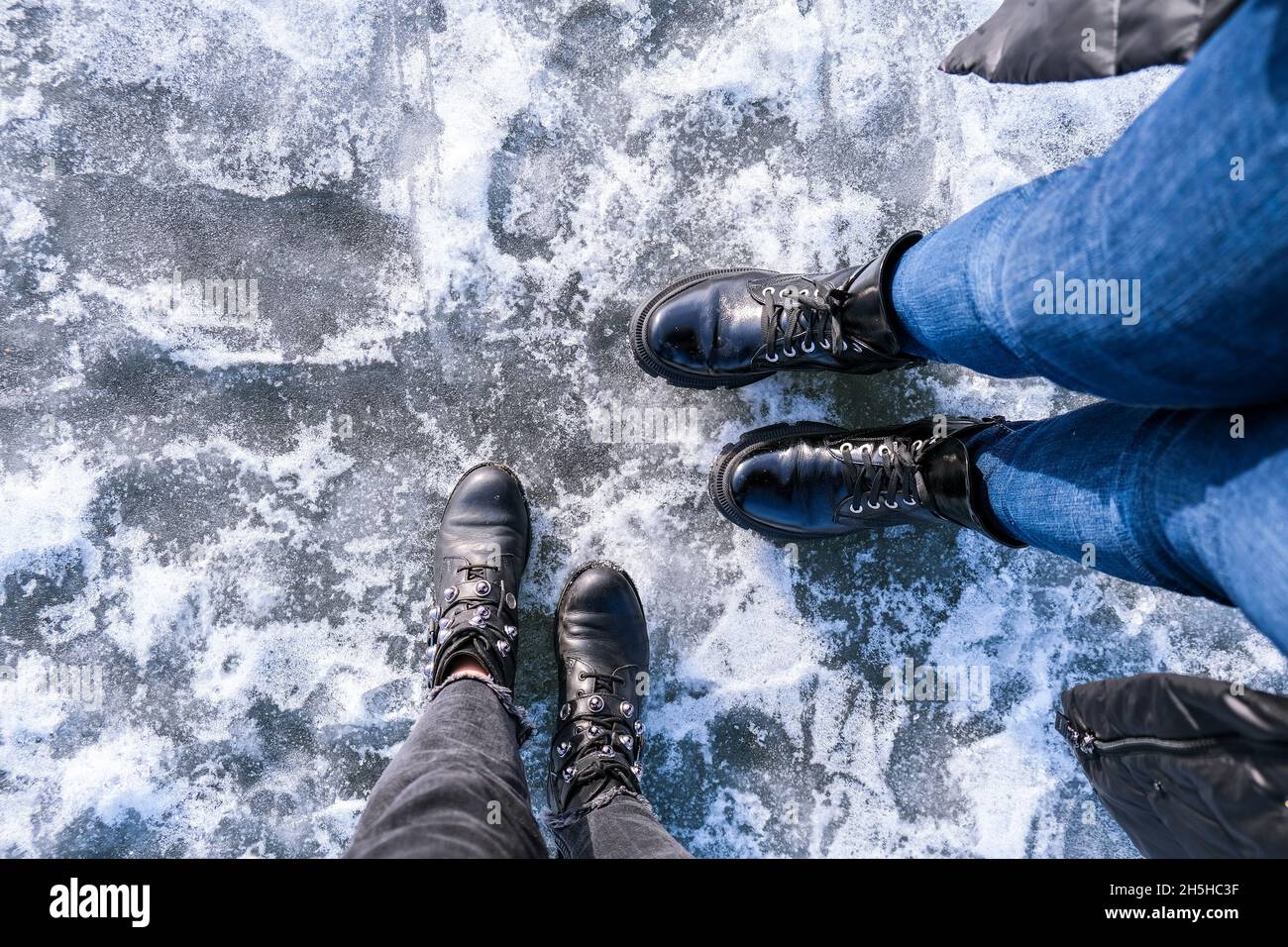 Two girls Looking down at feet. Frozen lake or river. Feet on ice ...