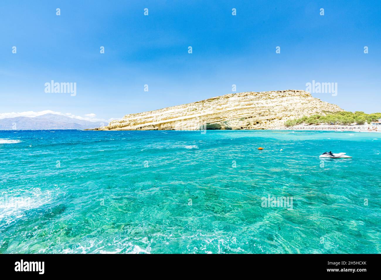 Caves carved into cliffs surrounded by the crystal sea, Matala, Crete ...