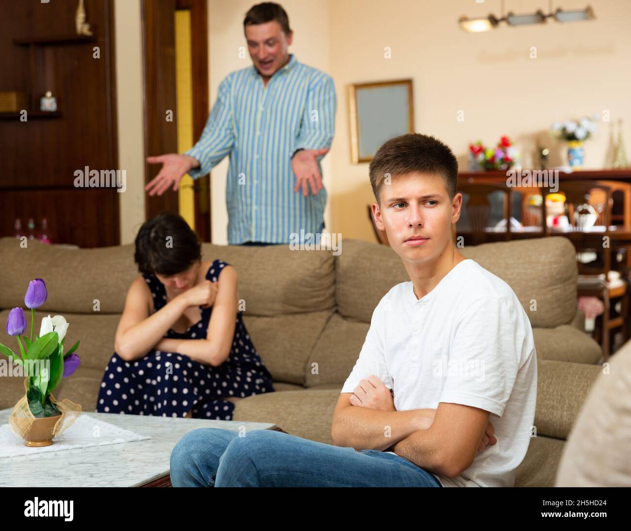 Unhappy guy sitting during his parents quarrelling Stock Photo - Alamy