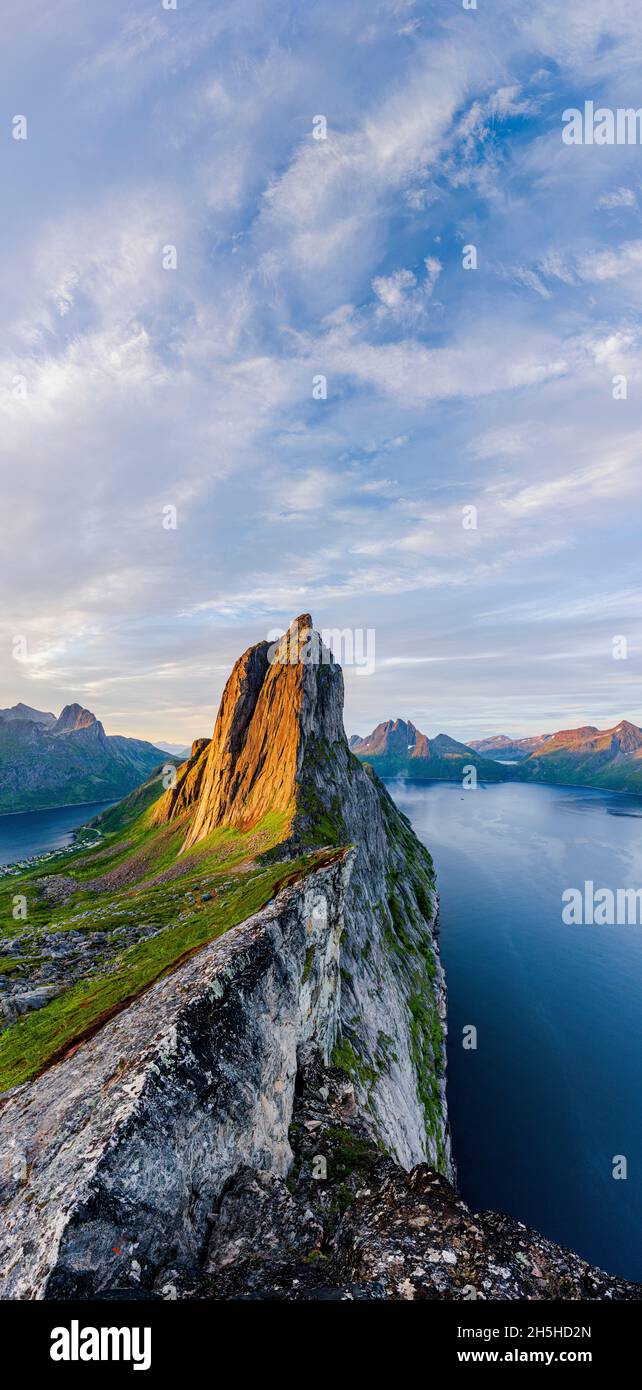 Blue water of fjord and majestic mountains lit by sunrise, Senja island ...