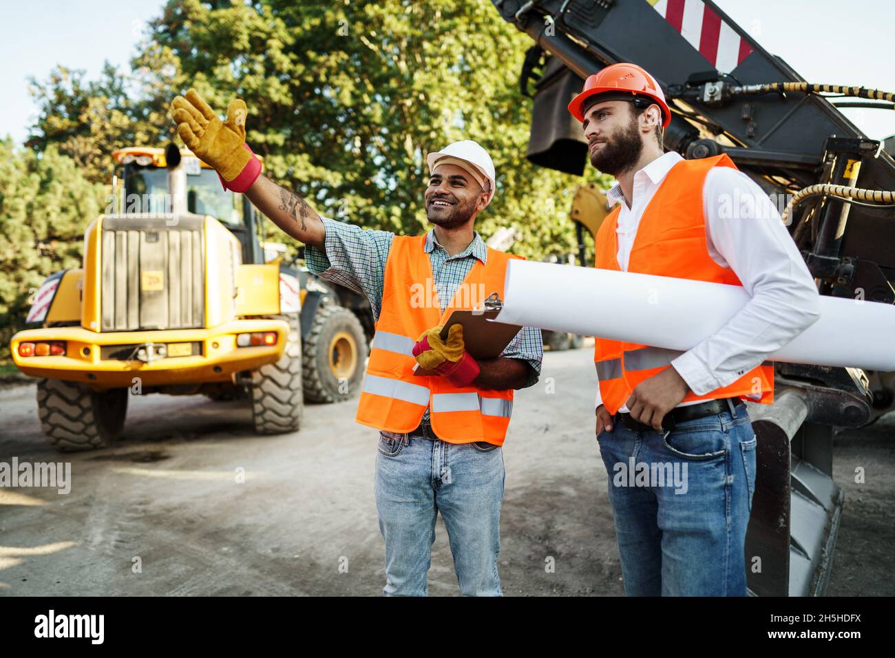 Two men engineers discussing their work standing against construction ...