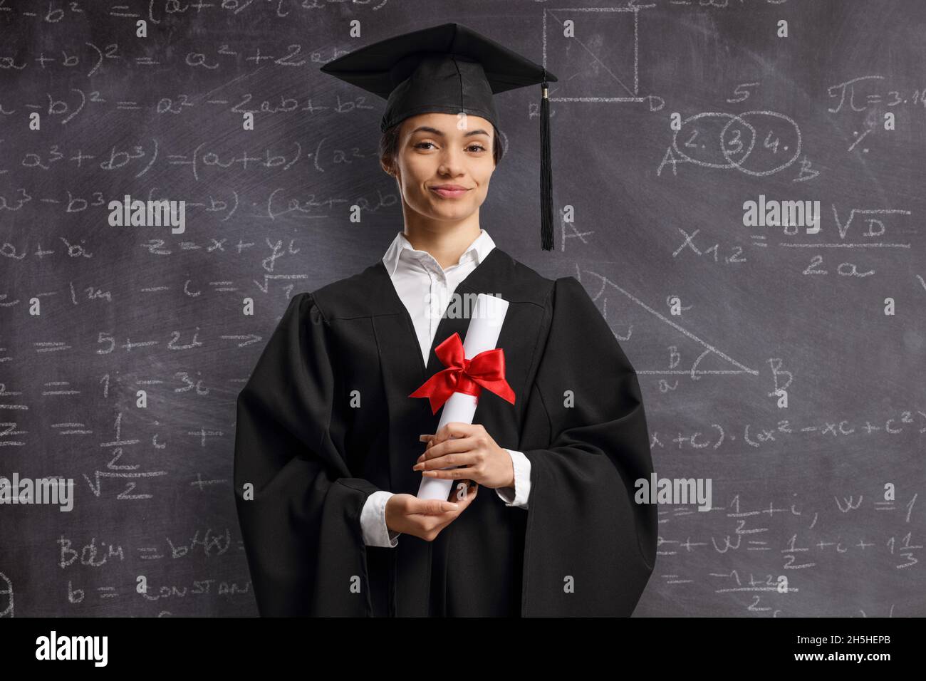 Female graduate student with diploma in front of a blackboard with math ...
