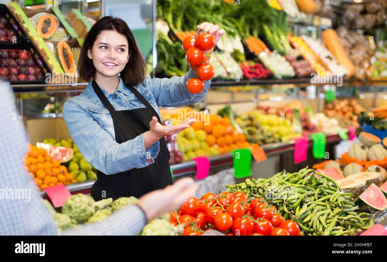 Female shopping assistant helping customer to buy fruit and vegetables ...