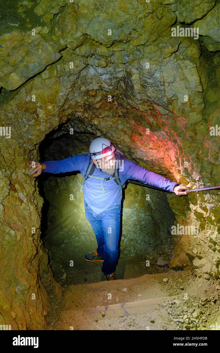 Climber with helmet and headlamp in rock tunnel, open-air museum First World War, tunnel path ...