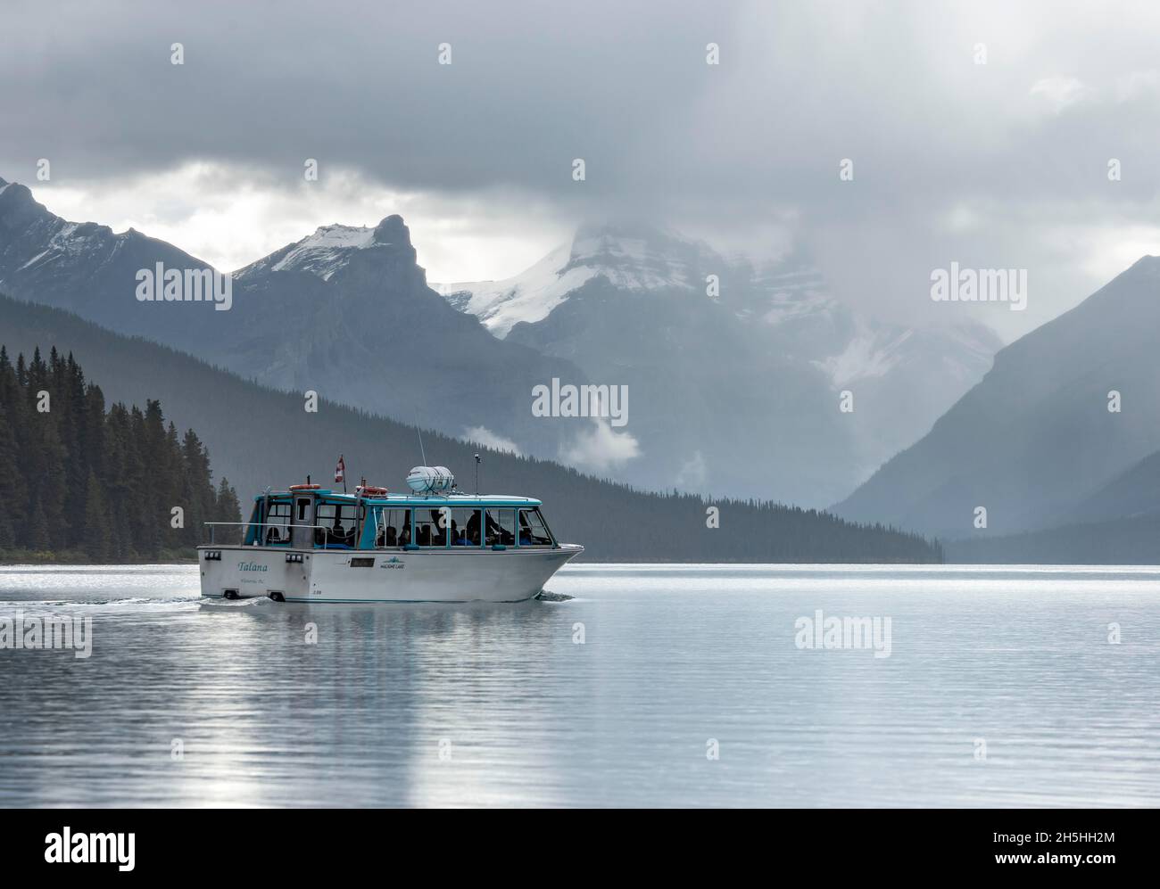 Boat on Maligne Lake, behind it mountain range Queen Elizabeth Ranges ...