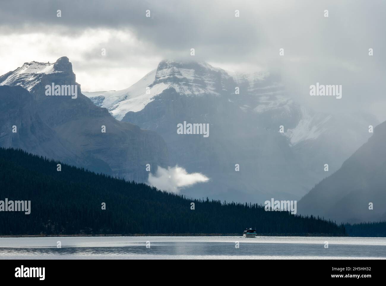 Boat on Maligne Lake, behind it mountain range Queen Elizabeth Ranges ...