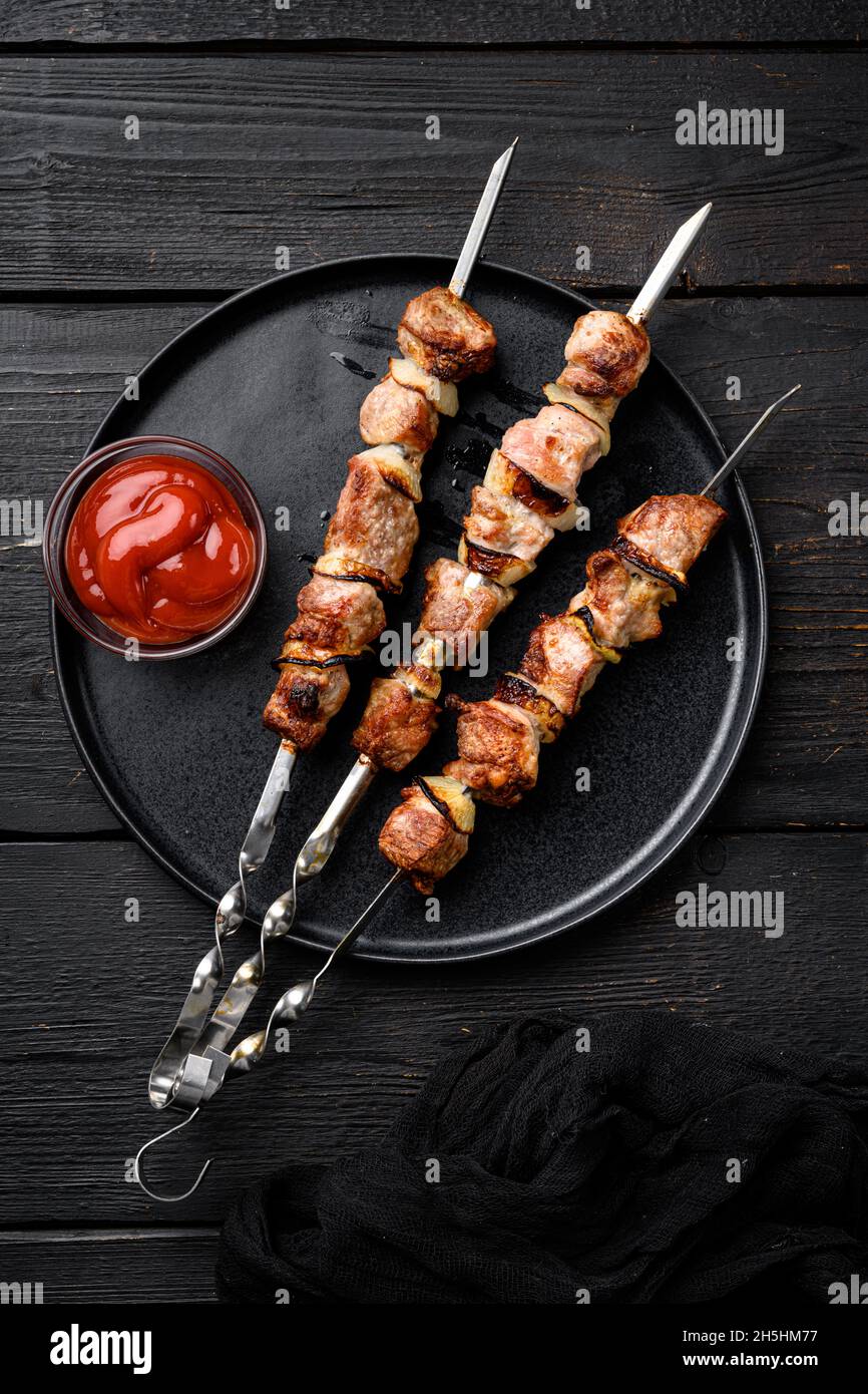 Shish kebab of pork set, on black wooden table background, top view ...