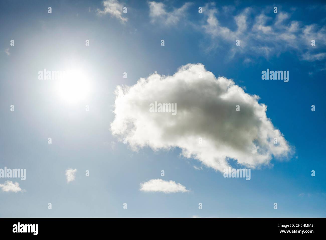The sun shines next to an cumulus cloud (Cumulus) cloud and a few feather clouds in the blue sky ...