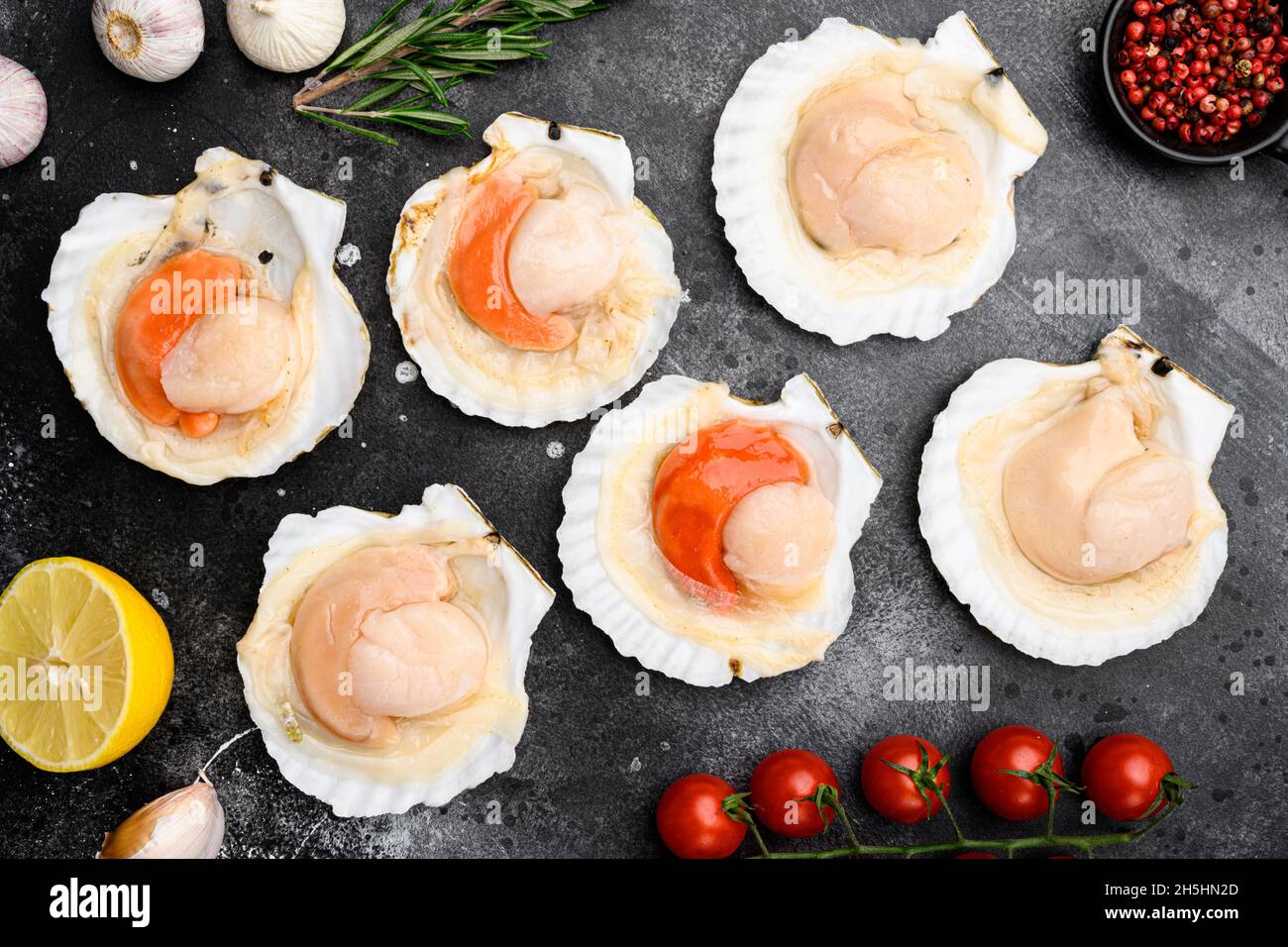 Seafood. Shellfish. Raw scallops with lemon set, on black dark stone ...
