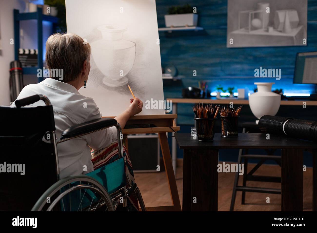 Disabled elder artist drawing vase design on canvas in artwork studio ...