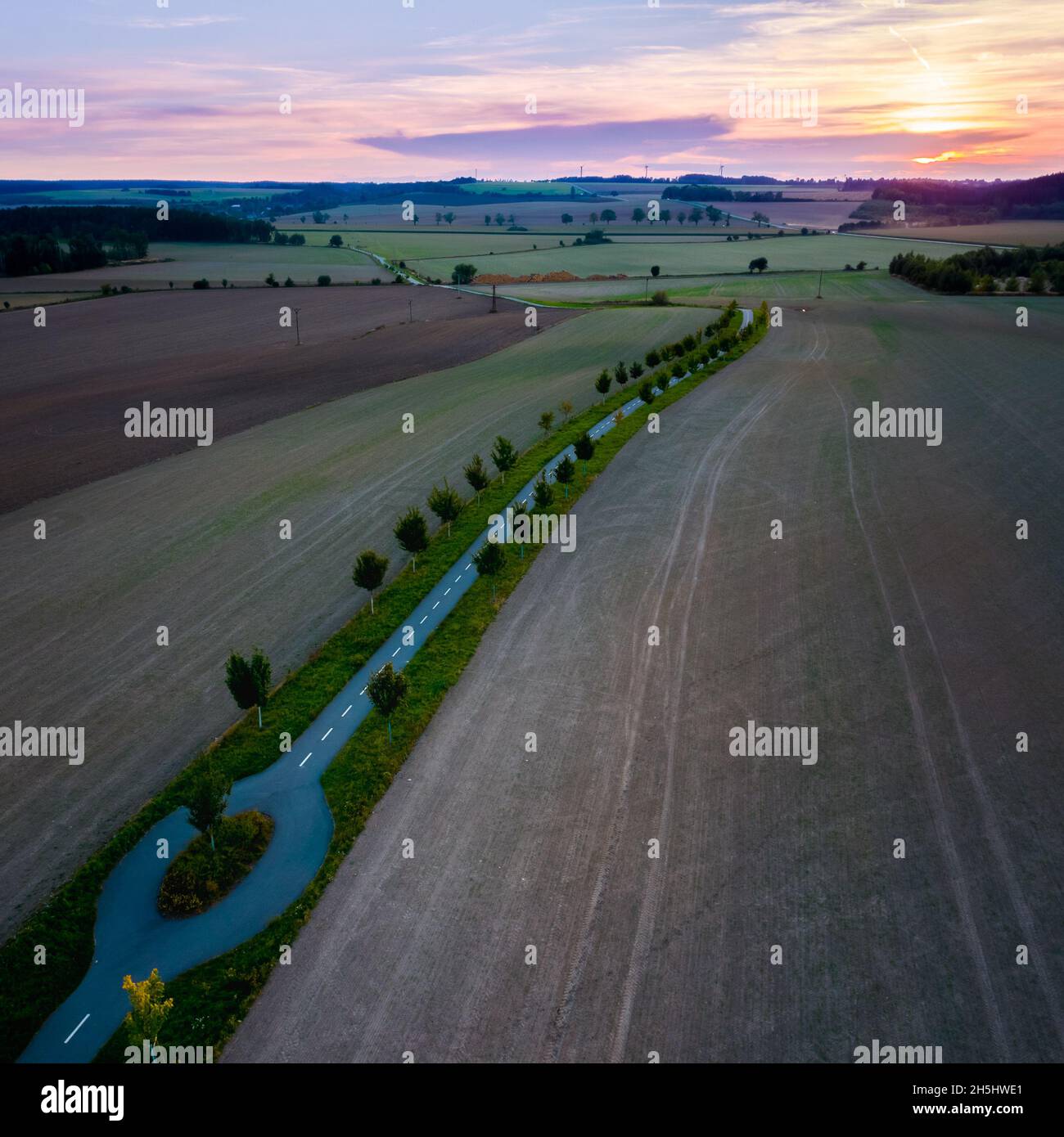 Beautiful shot of a long green road at sunset Stock Photo - Alamy