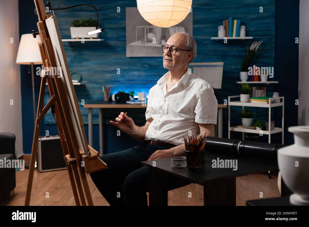 Elder artist with creativity holding pencil to draw on canvas with ...