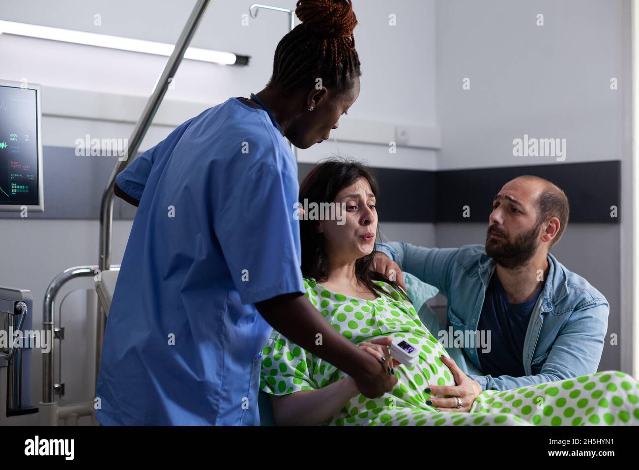 Medical assistant holding hand of pregnant woman sitting in hospital ...