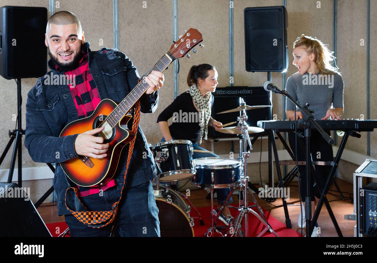 Guy guitar player and singer practicing with band members in recording ...