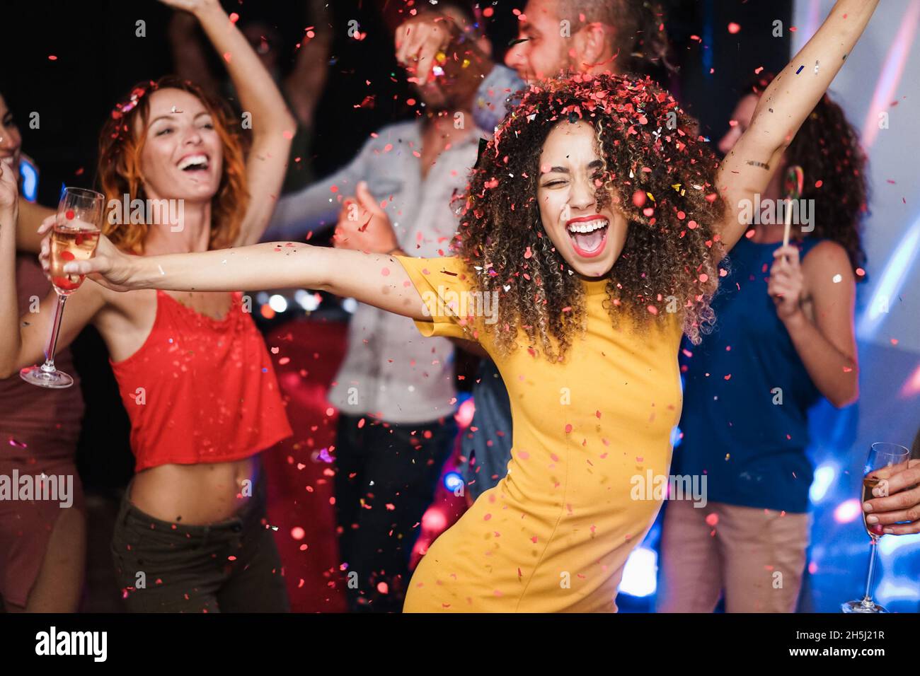 Young multiracial people dancing and celebrating with champagne at ...