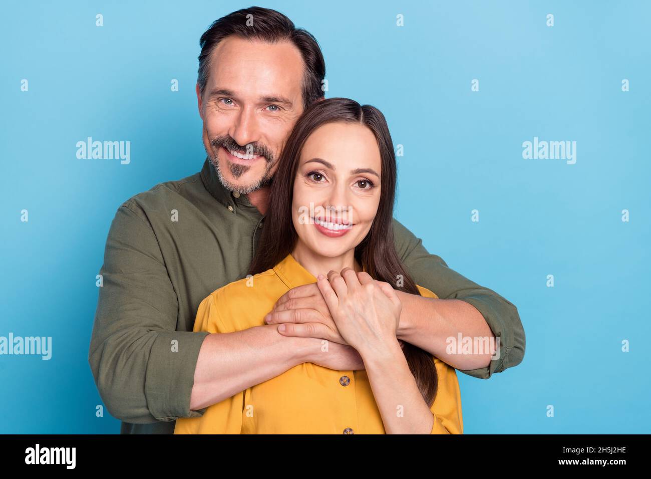 Photo of happy cheerful mature man and woman married hug harmony smile enjoy isolated on blue ...