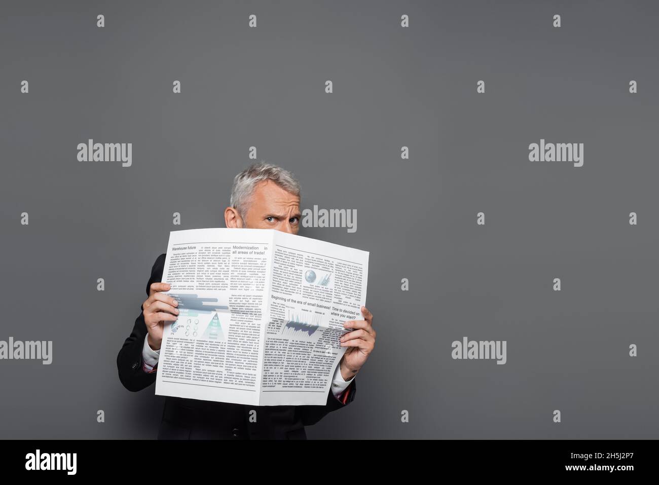middle aged businessman covering face with newspaper on grey Stock ...