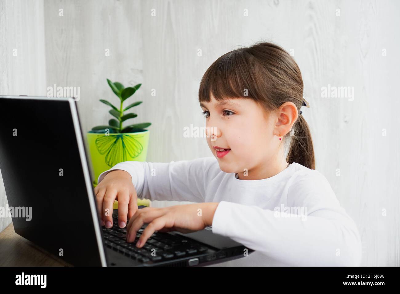 Indoor shot of cute dark haired female child looking at notebook ...