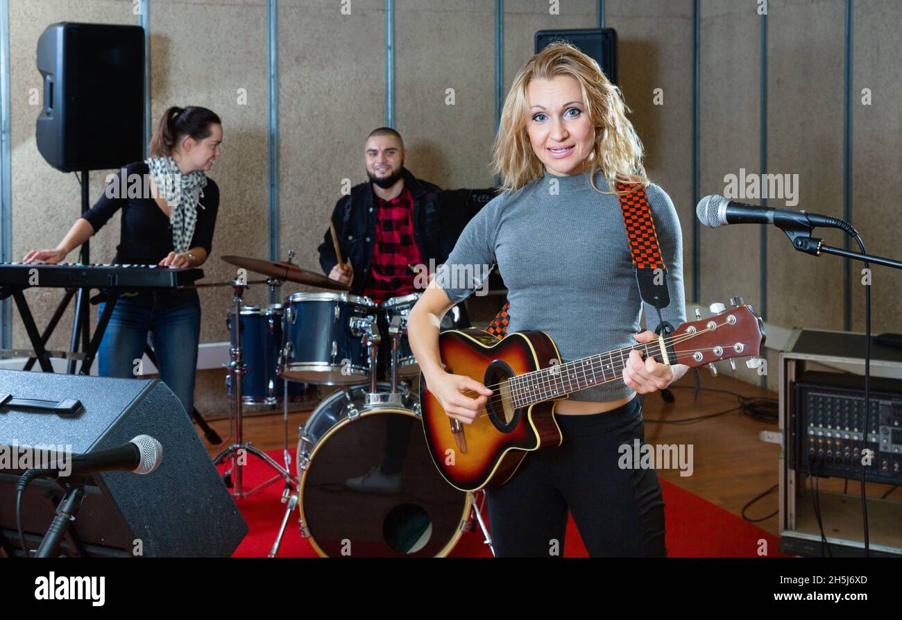 Attractive female soloist playing guitar and singing with her music ...