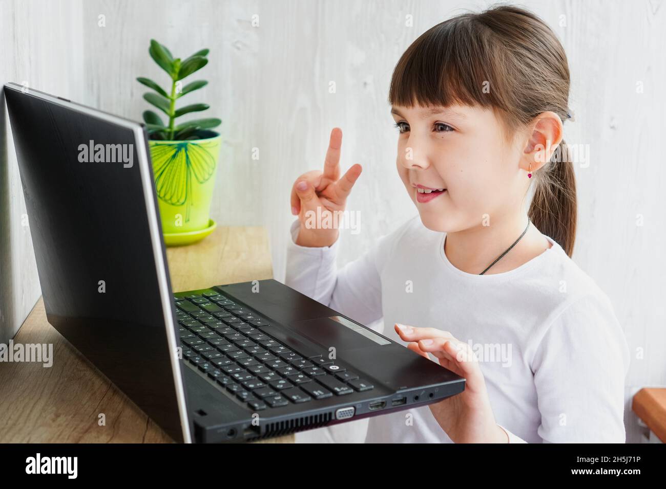 Indoor shot of cute dark haired female child looking at notebook ...