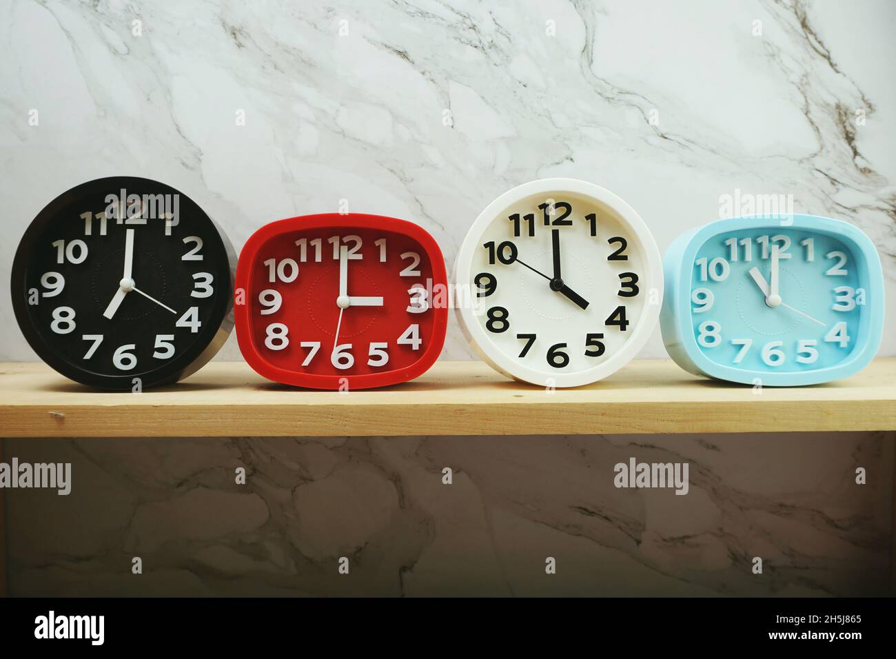 Clocks with time zone of different country on wooden shelves and marble ...