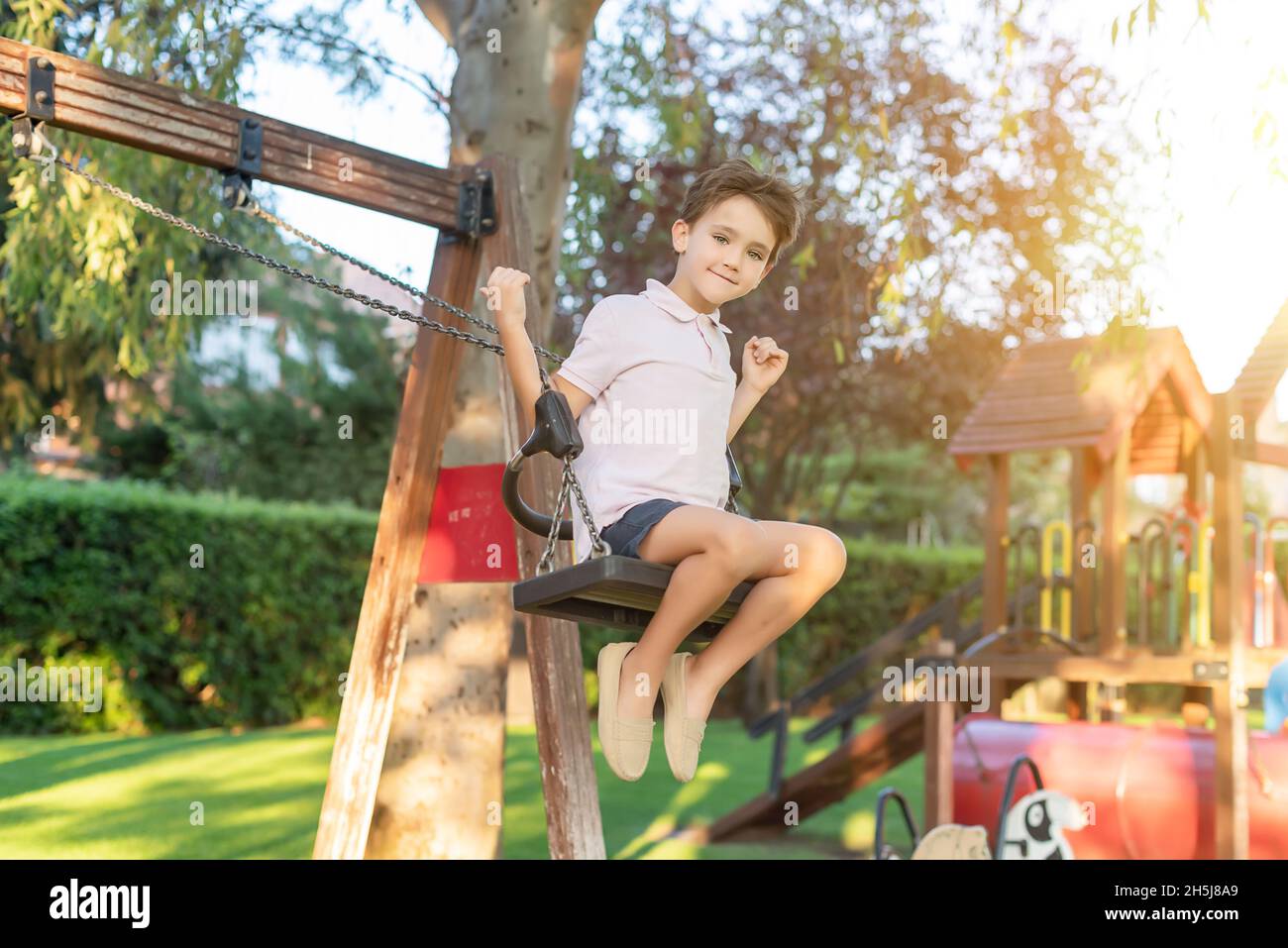 Side view of a child playing on a swing in a playground Stock Photo - Alamy