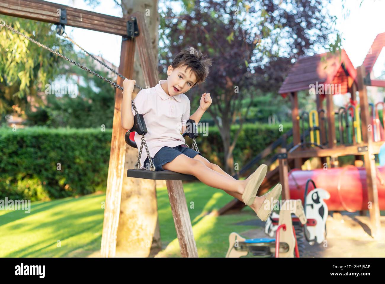 Side view of a child playing on a swing in a playground Stock Photo - Alamy