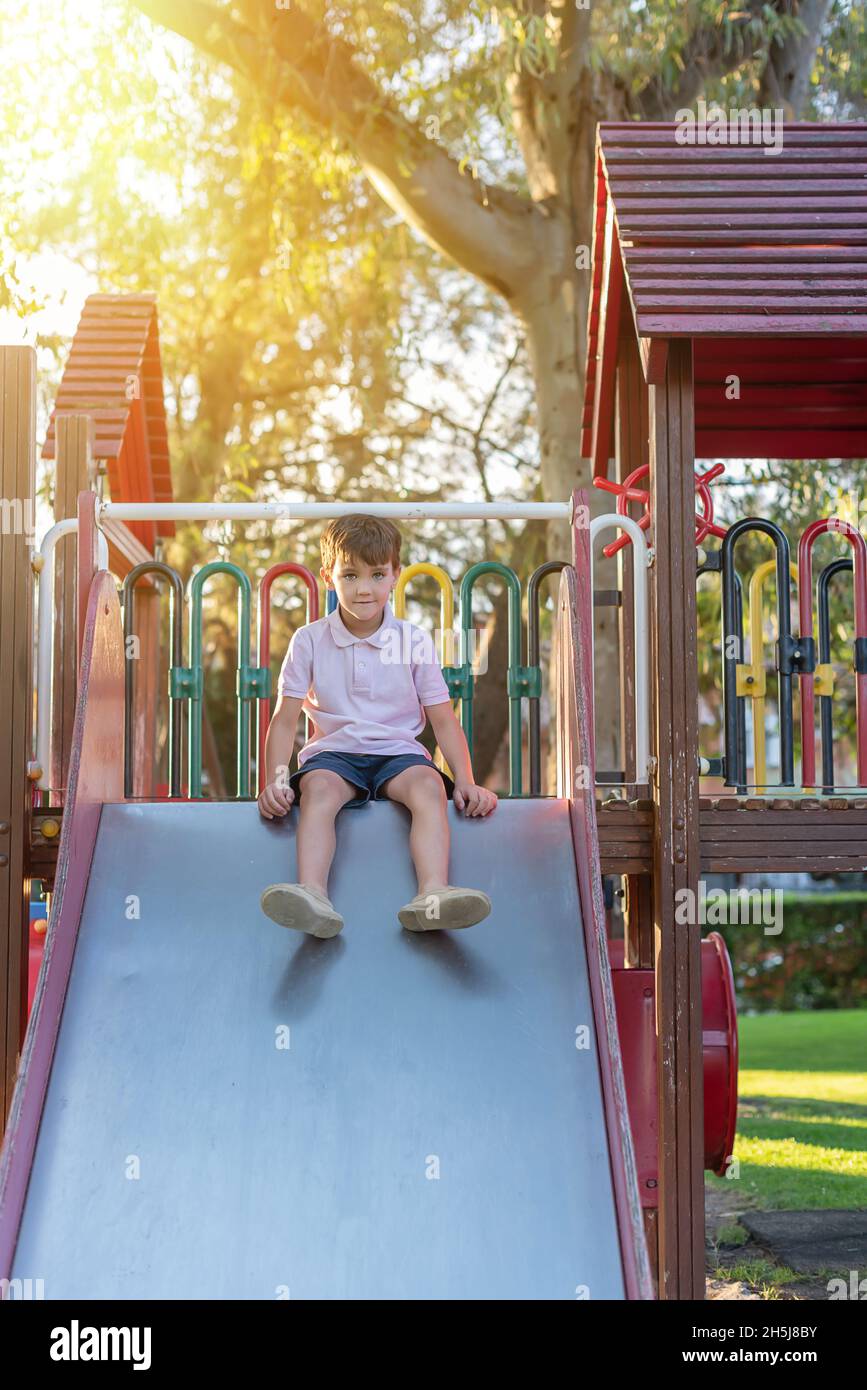 Child sitting on a slide at a children's playground Stock Photo - Alamy