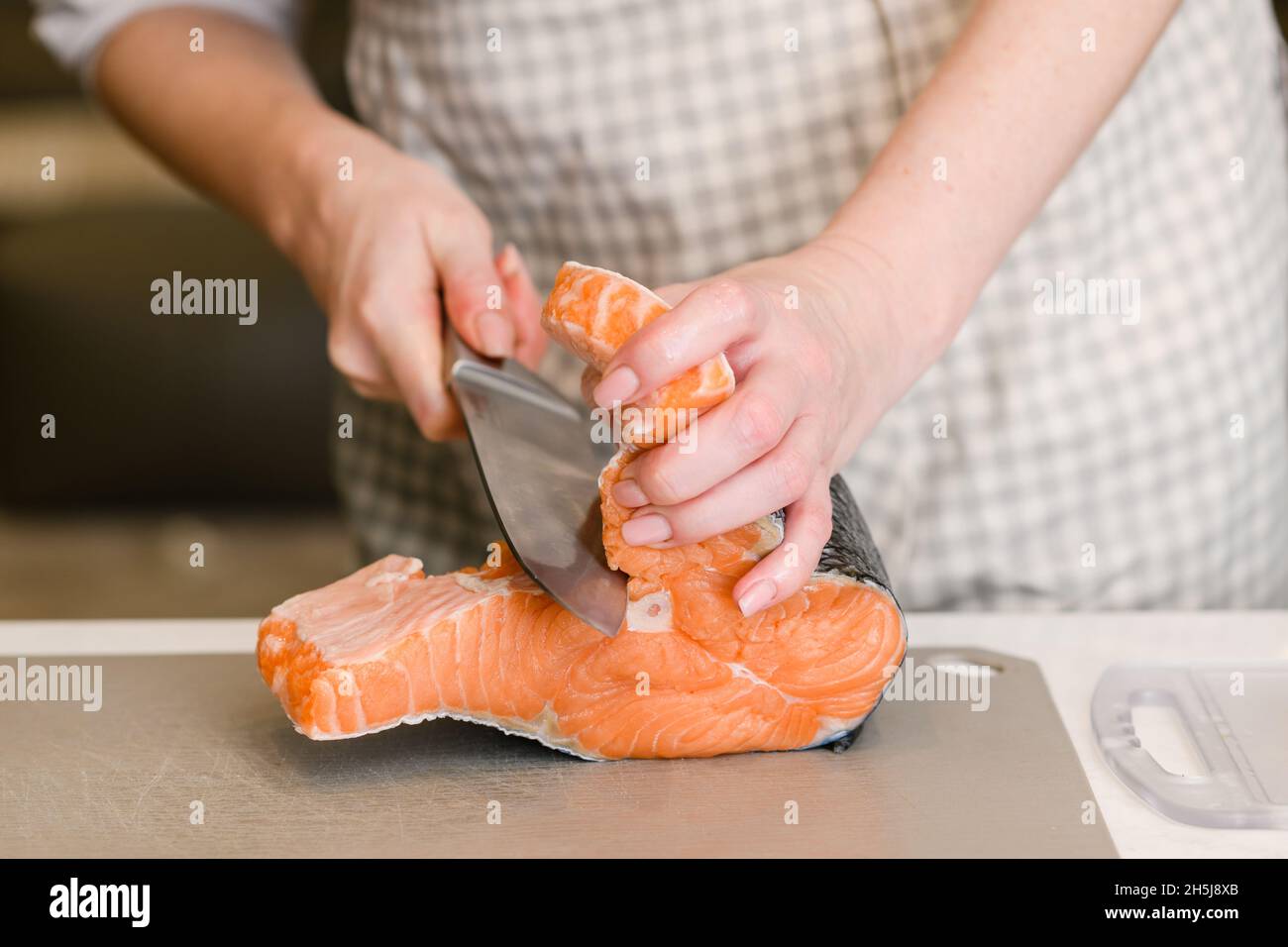 Removing fish bones. Woman in an apron prepares red fish fillets for ...