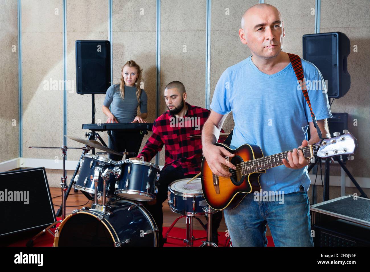 Rehearsal of music group. Band leader playing guitar and singing with ...