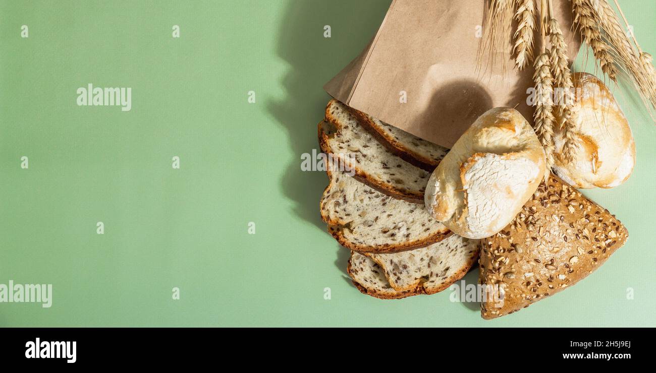 Assorted freshly baked bread with wheat ears, buns, and toasts. Paper ...