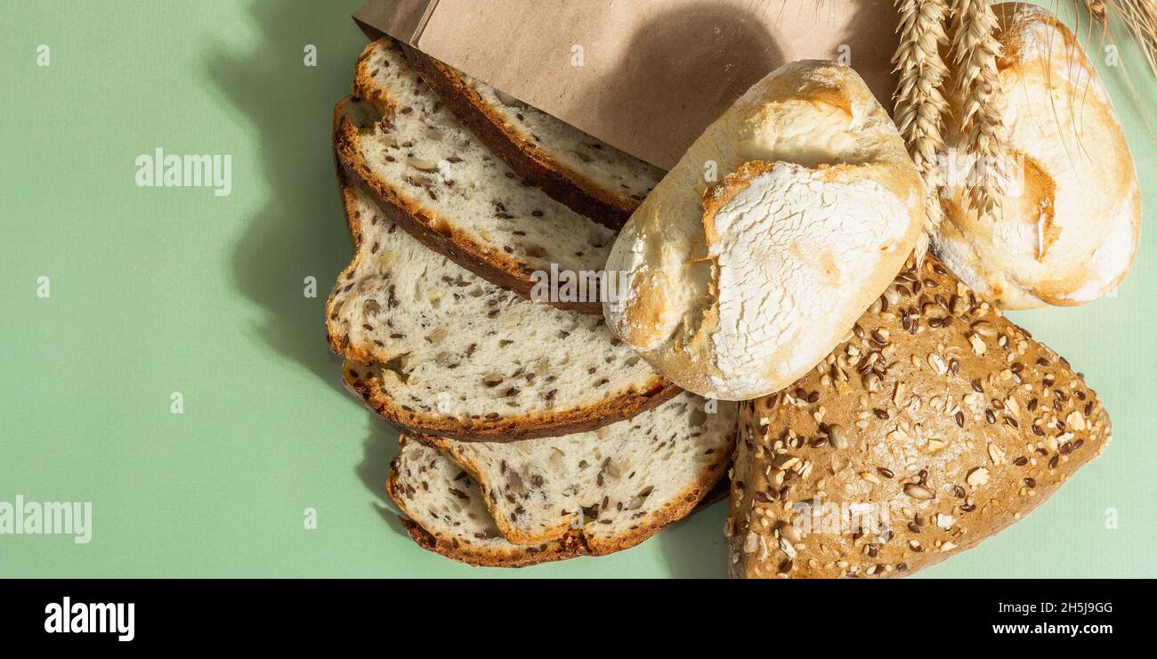 Assorted freshly baked bread with wheat ears, buns, and toasts. Paper ...