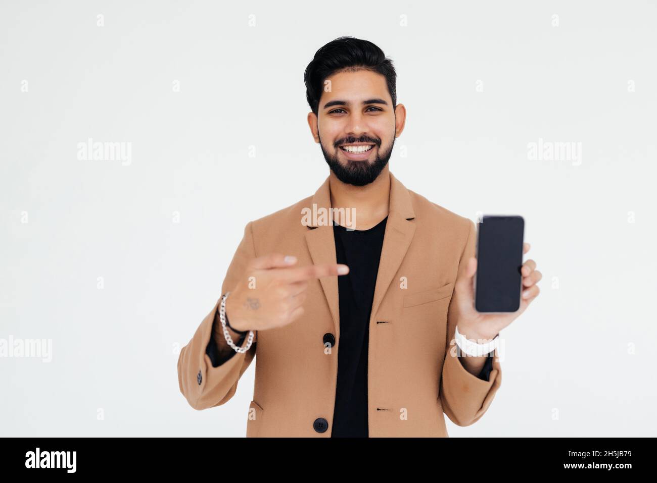 Portrait of a smiling cheerful man pointing finger at blank screen ...